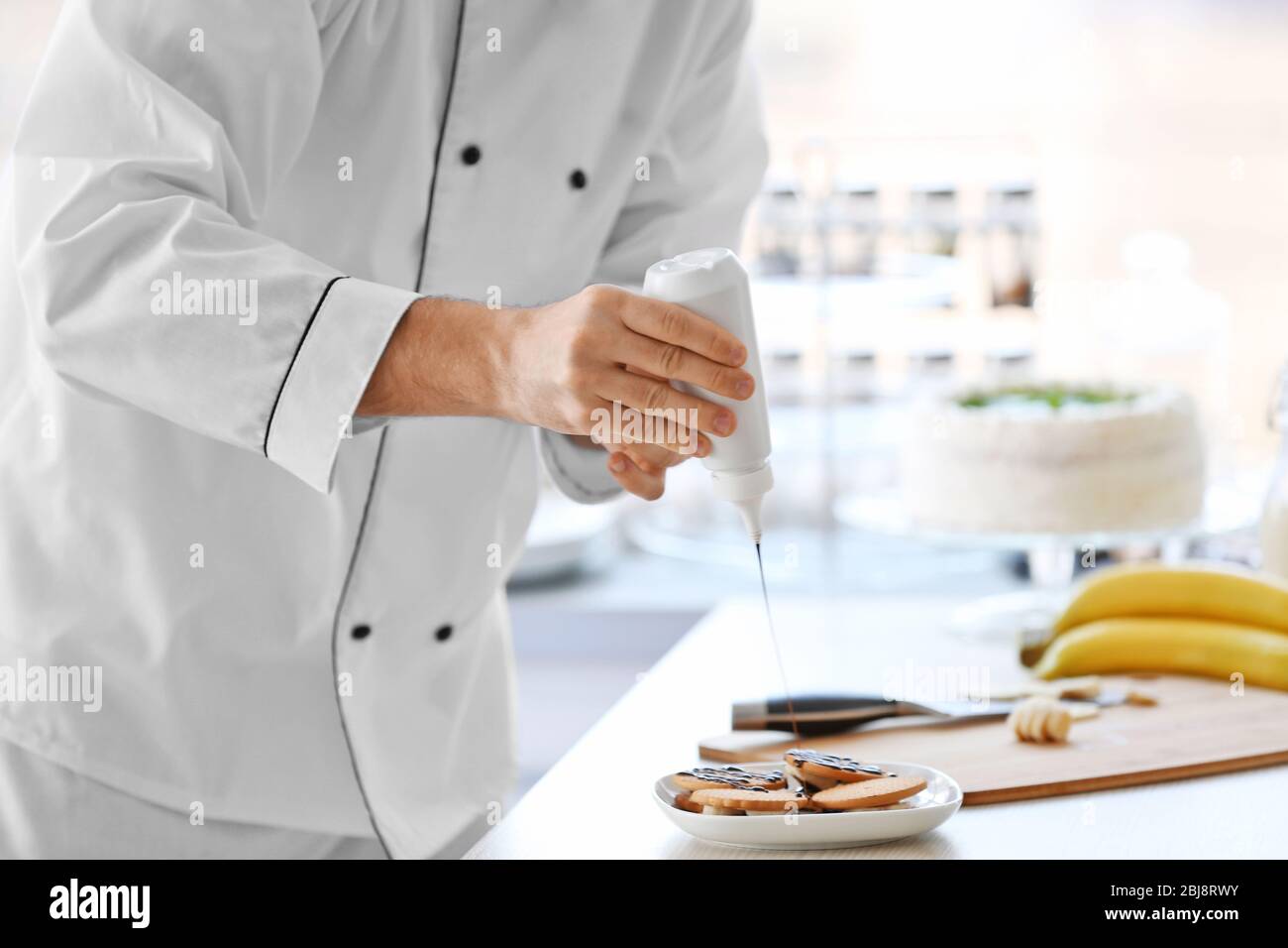 Male chef decorating cookies with chocolate Stock Photo - Alamy