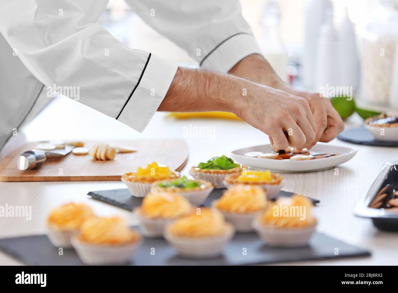 Male chef decorating cookies with sliced banana Stock Photo - Alamy