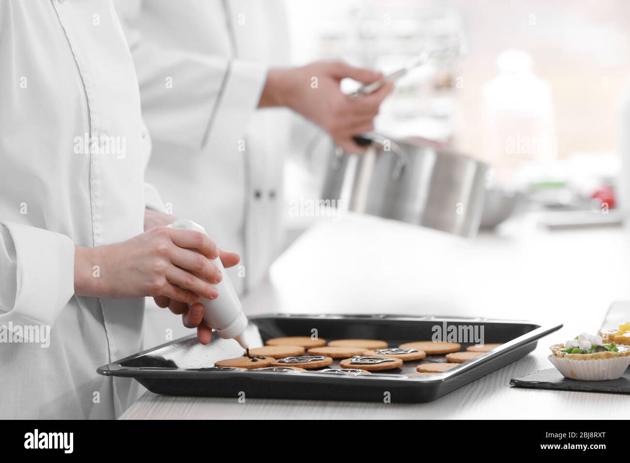 Chefs decorating cookies with chocolate Stock Photo - Alamy