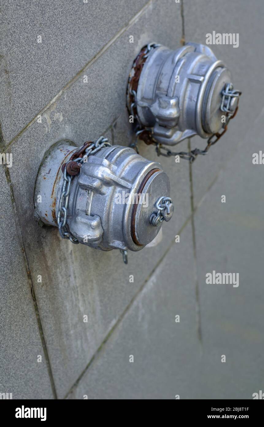 Aluminum fire hydrants in the wall with covers on chains. Two fire ...