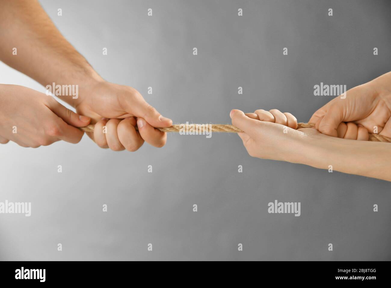 Teamwork concept. People hands pulling the rope on grey background ...