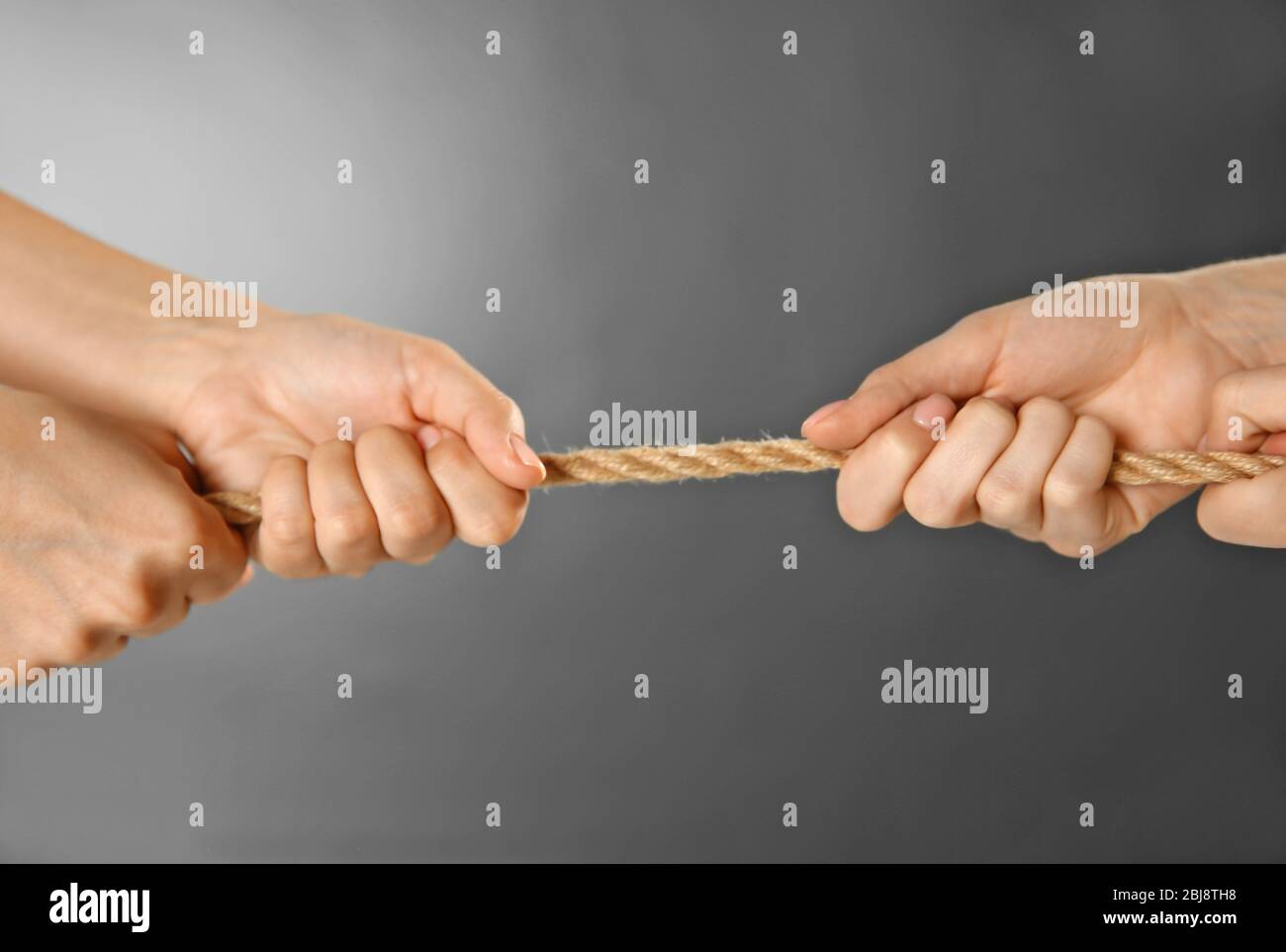 Teamwork concept. People hands pulling the rope on grey background ...