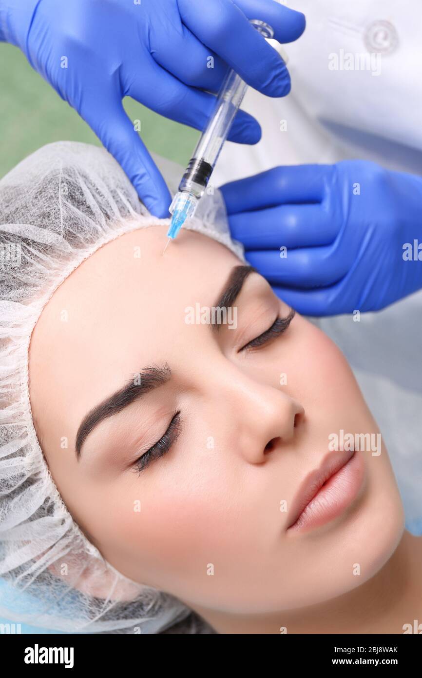 Young woman receiving plastic surgery injection on her face, closeup ...