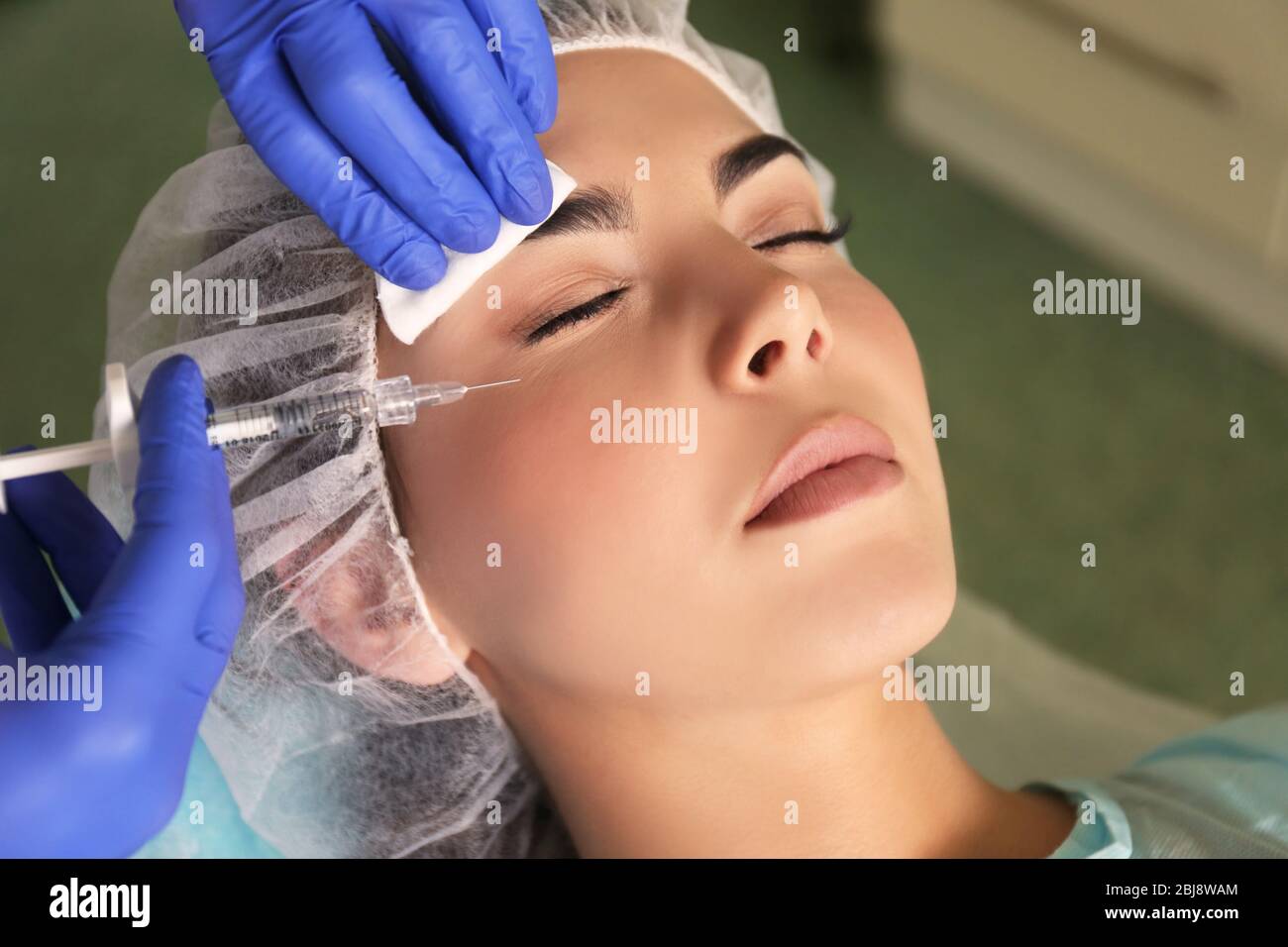 Young woman receiving plastic surgery injection on her face, closeup ...
