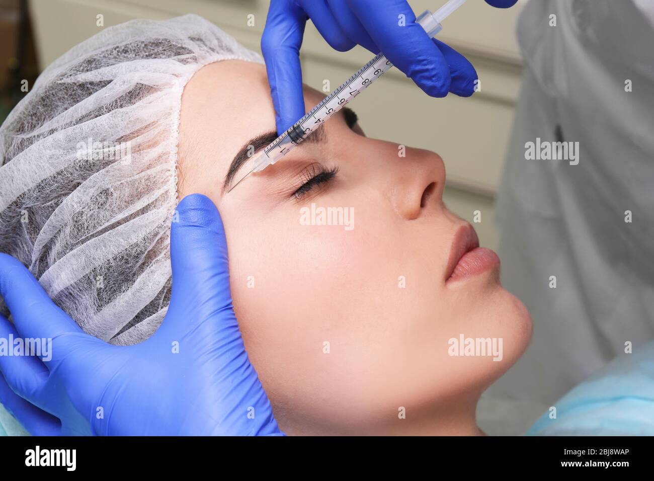 Young woman receiving plastic surgery injection on her face, closeup ...