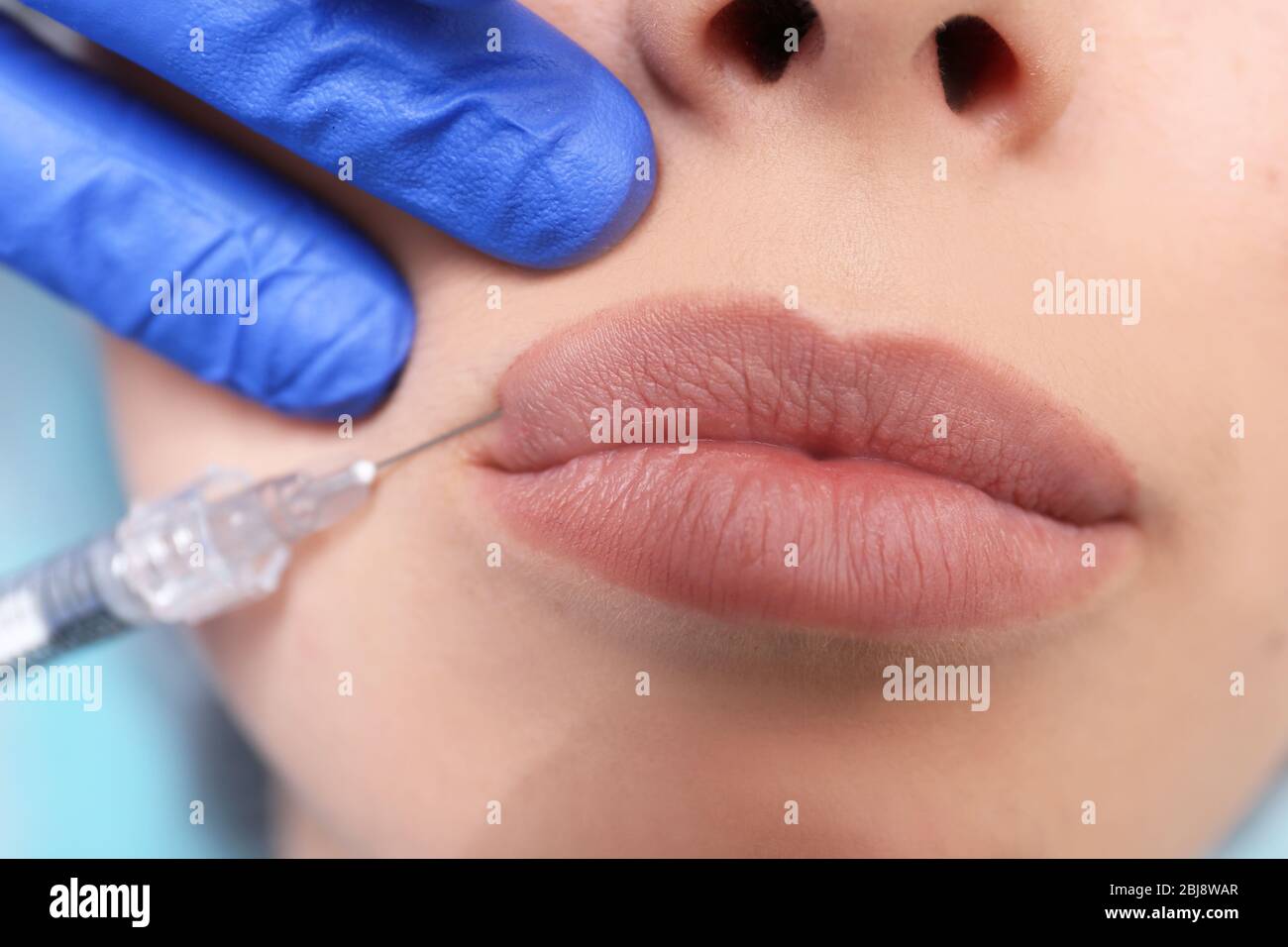 Young woman receiving plastic surgery injection on her face, closeup ...