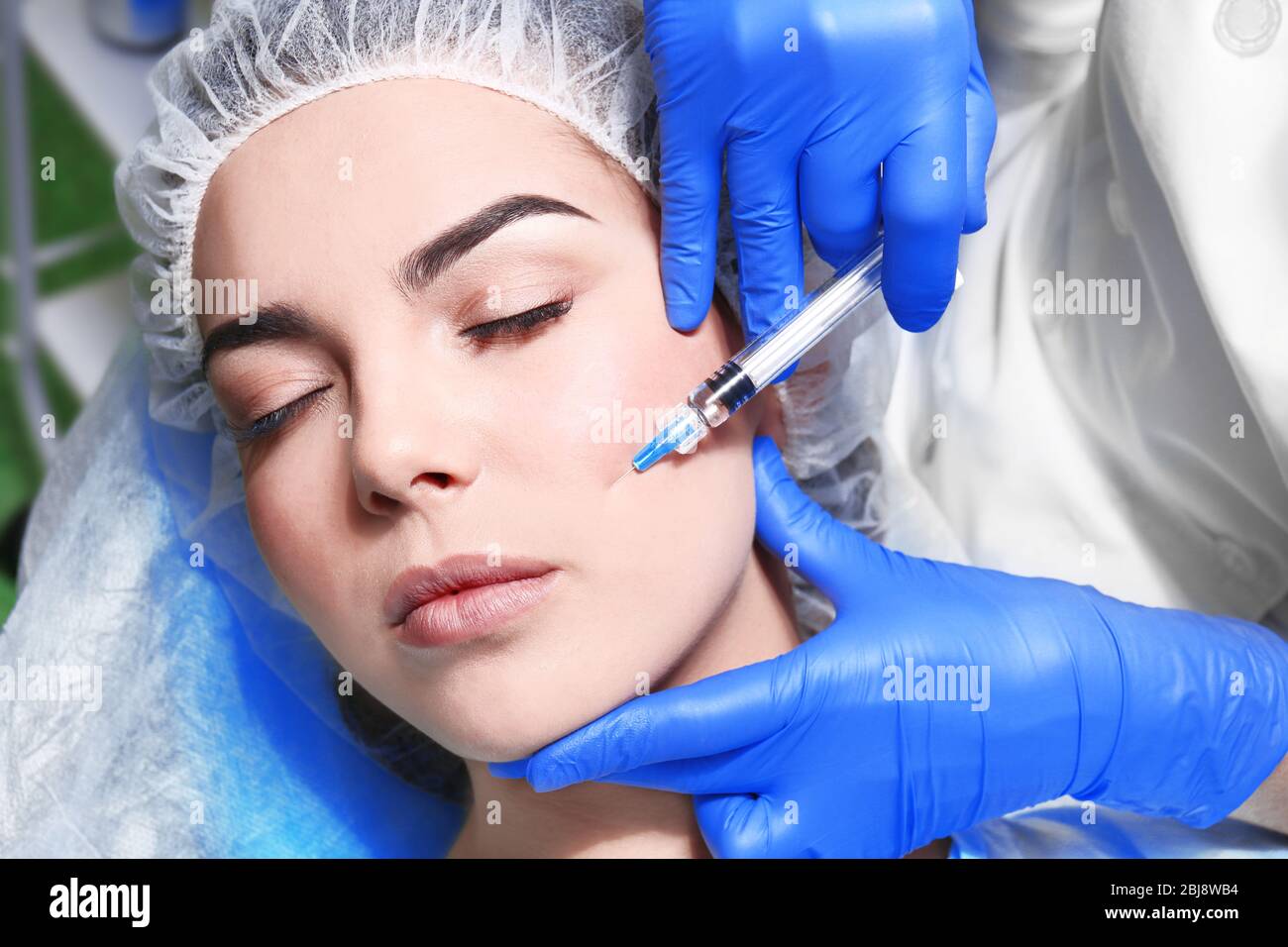 Young woman receiving plastic surgery injection on her face, closeup ...