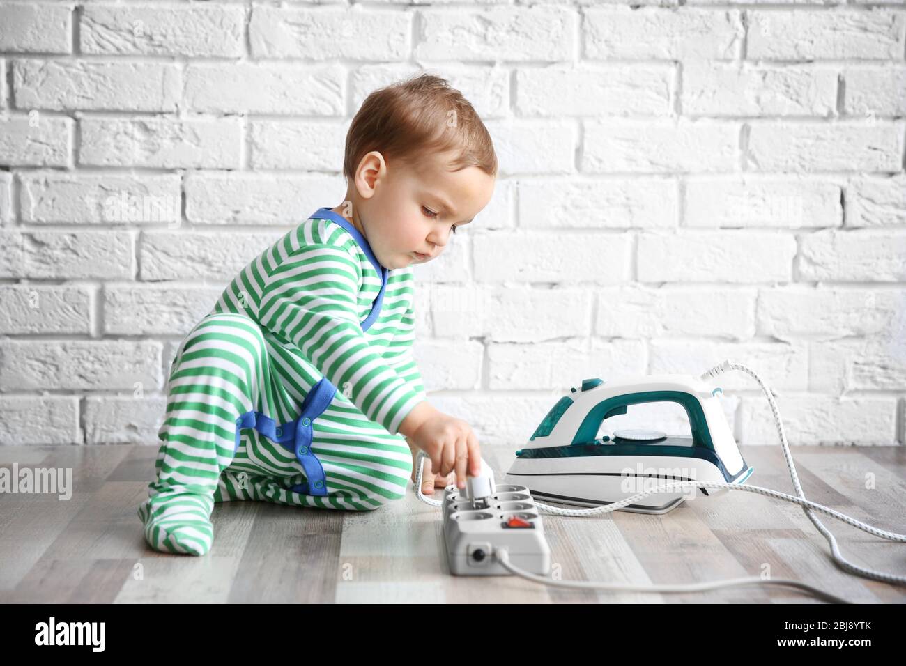 Little child playing with iron and electric power bar at home Stock ...