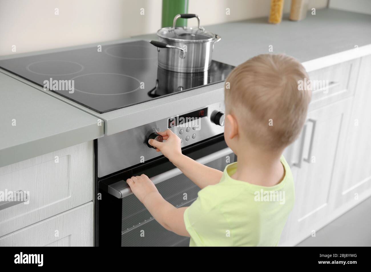 Little child playing with electric stove in the kitchen Stock Photo - Alamy