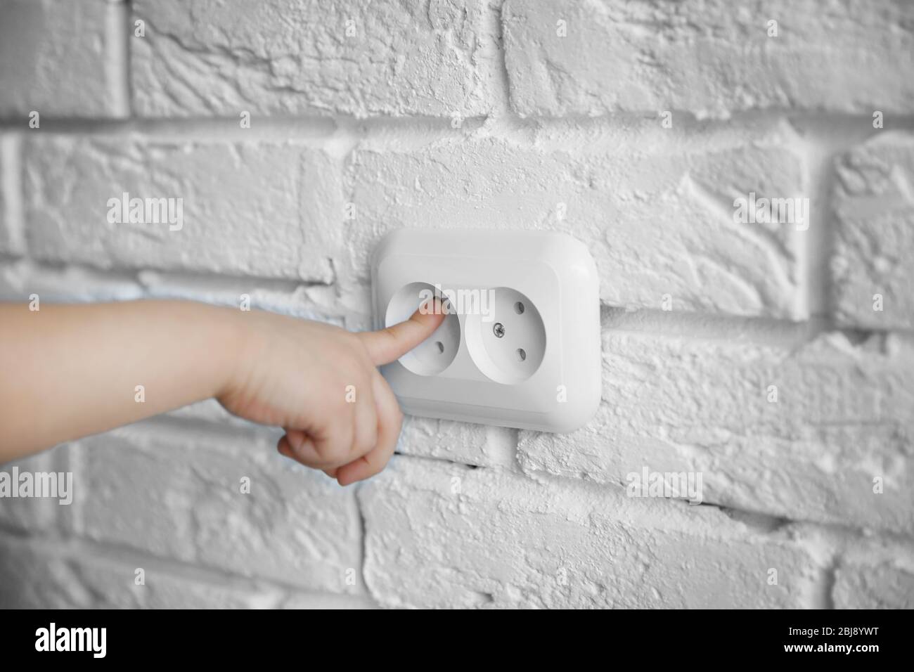 Little baby playing with socket on the wall Stock Photo - Alamy