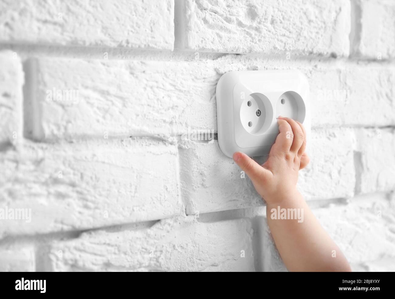 Little baby playing with socket on the wall Stock Photo - Alamy
