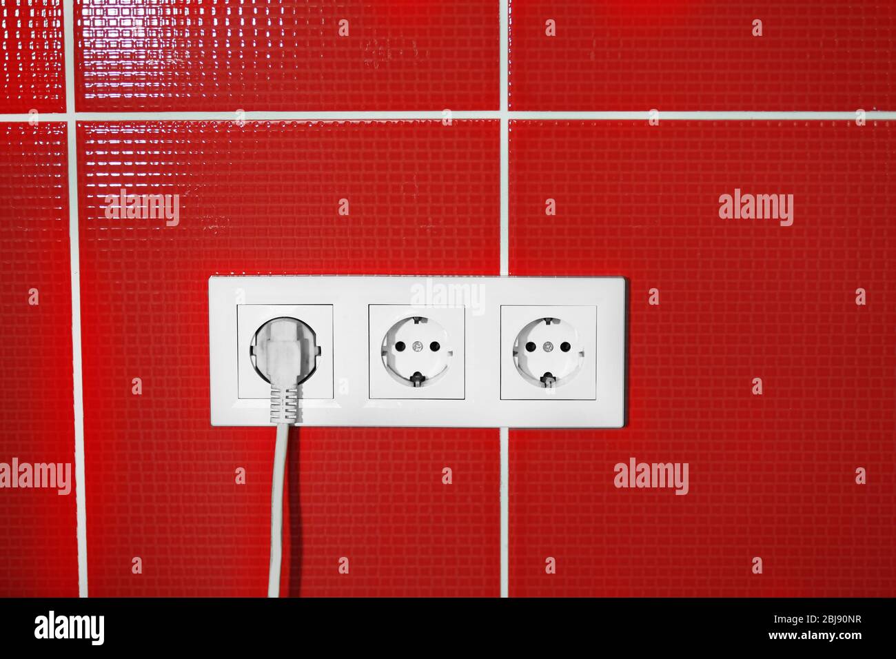 Sockets on red tiled wall background Stock Photo - Alamy