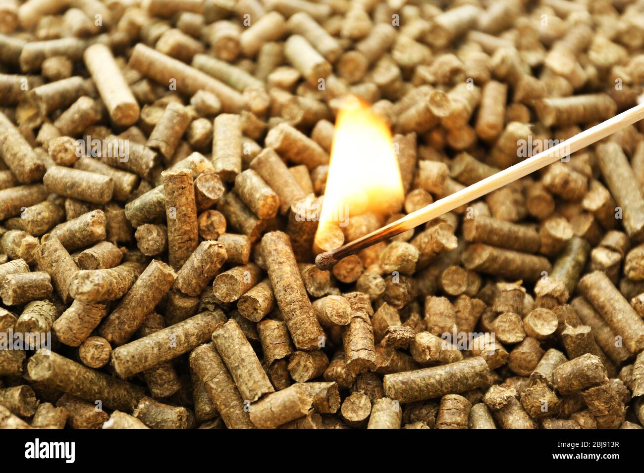 human hand holding burning match on solid pellets background Stock ...