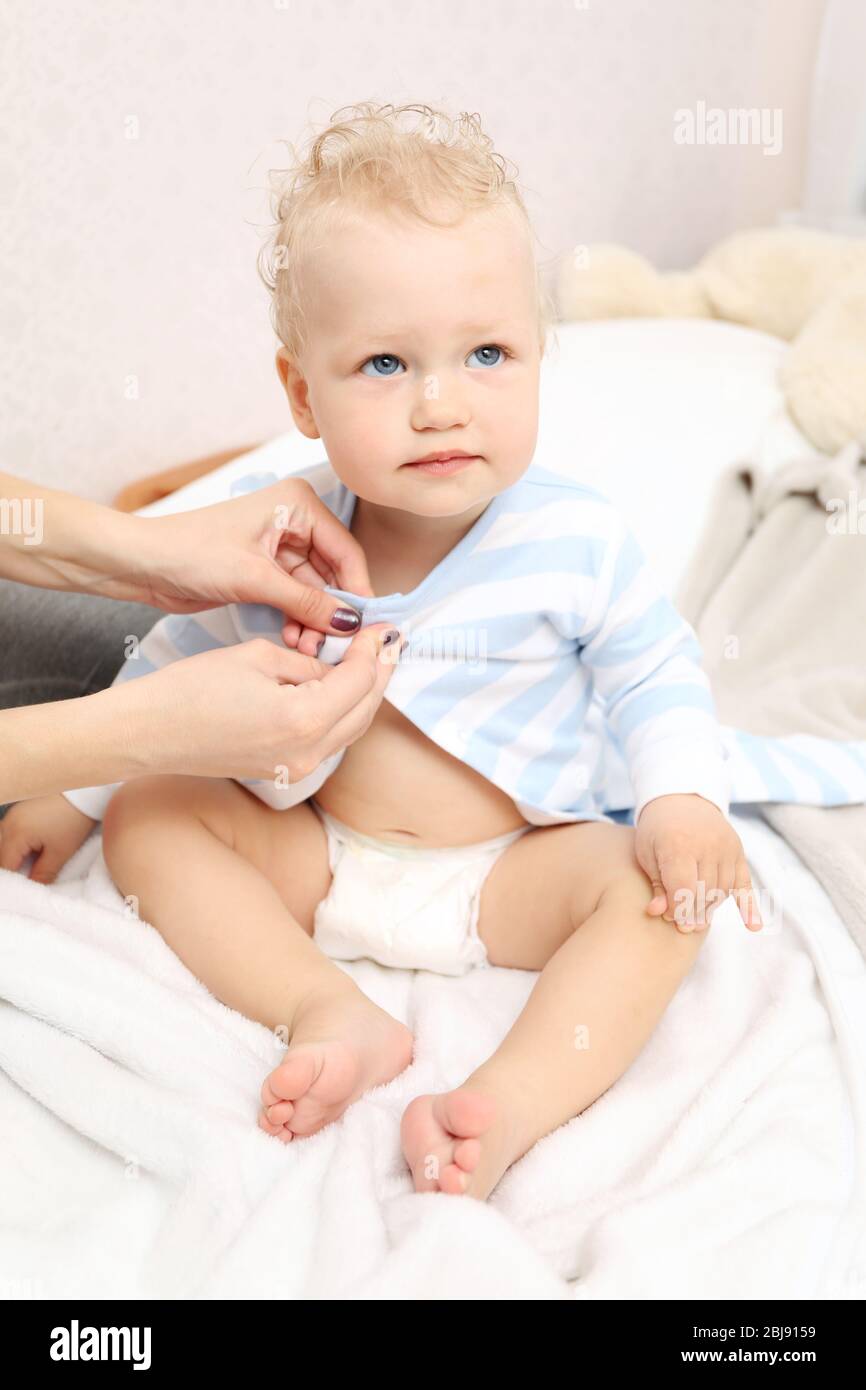 Mother dressing her baby on bed Stock Photo - Alamy