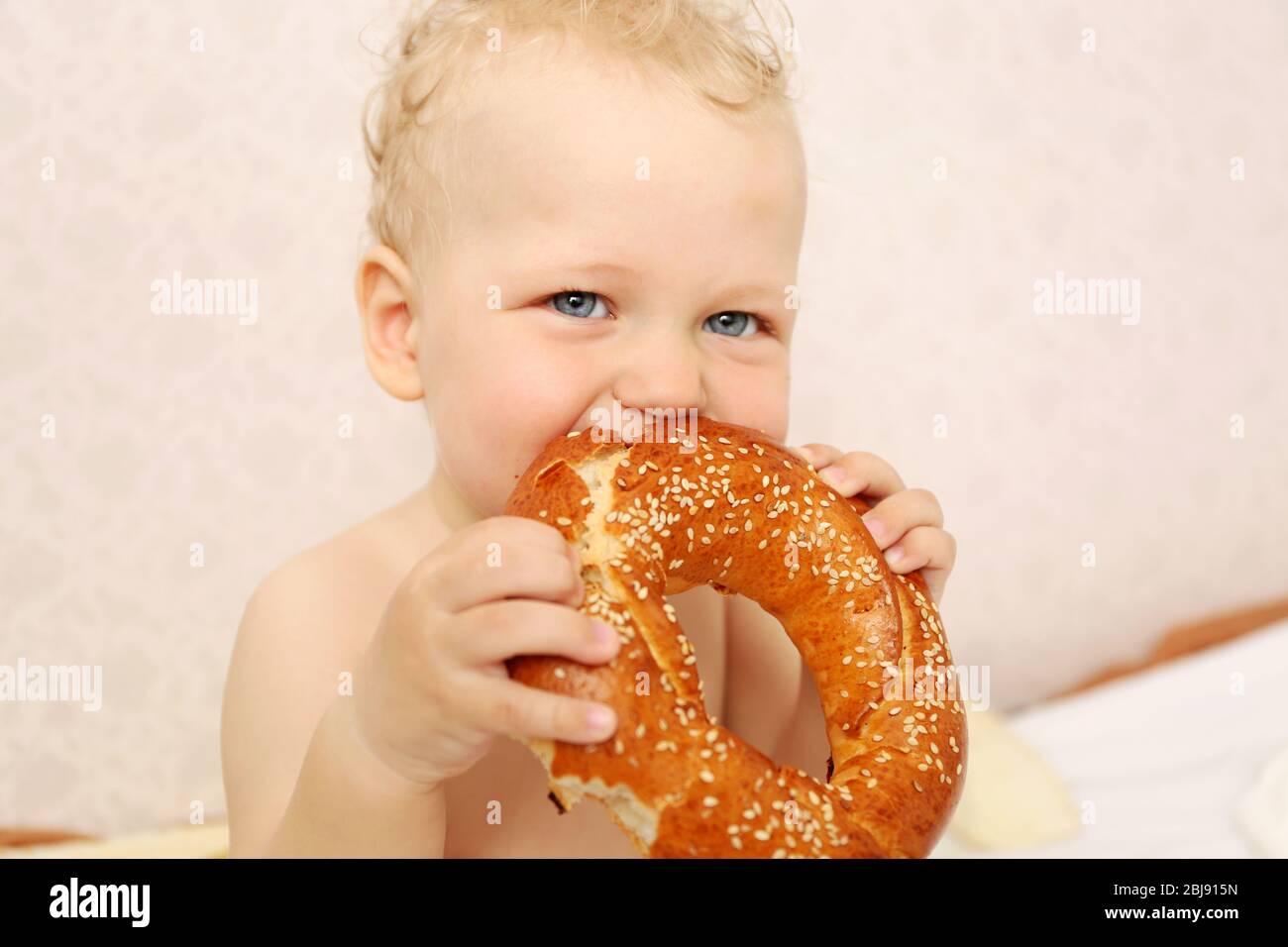 Little baby eating bun on bed Stock Photo - Alamy
