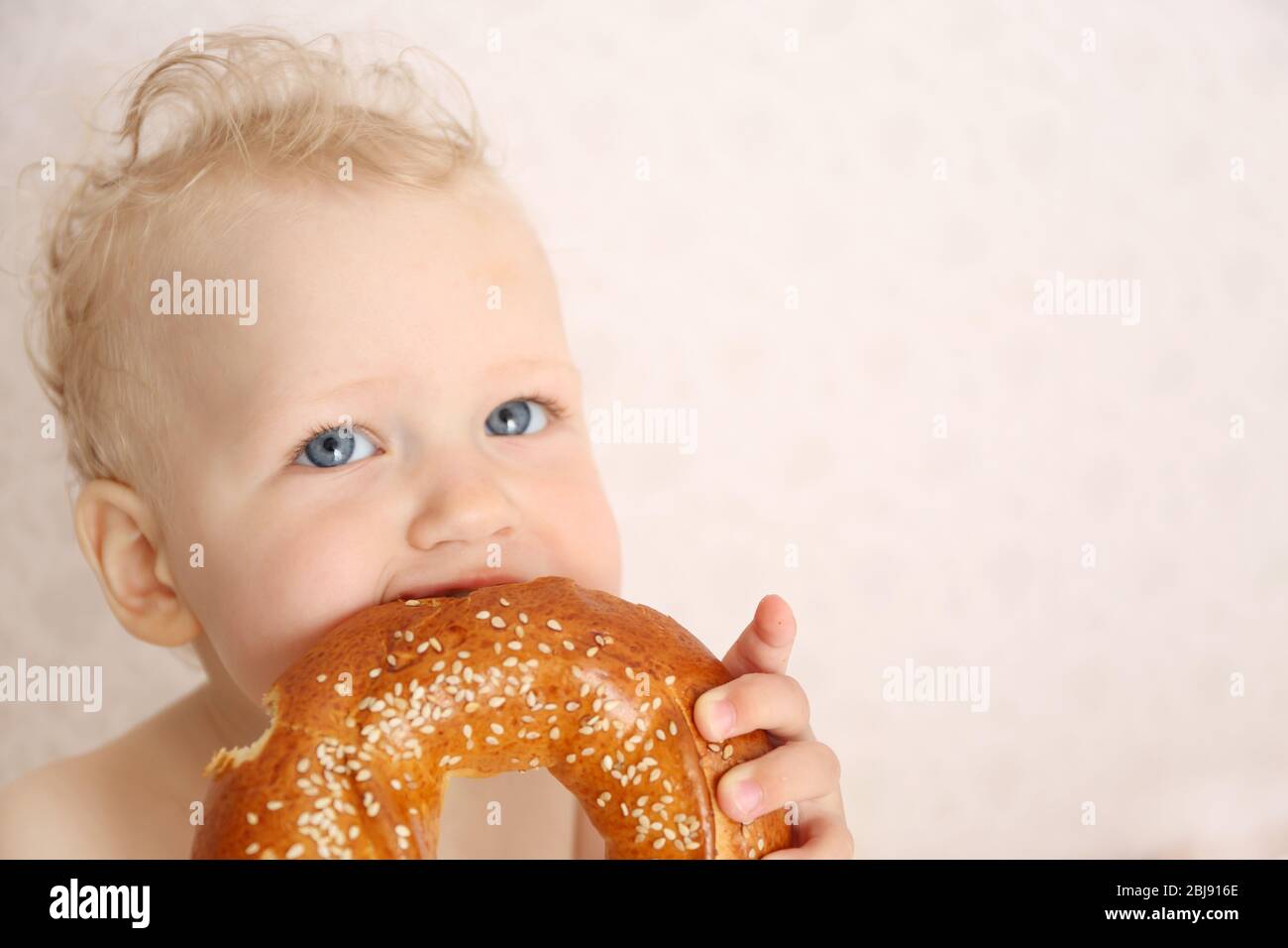 Little baby eating bun on bed Stock Photo - Alamy