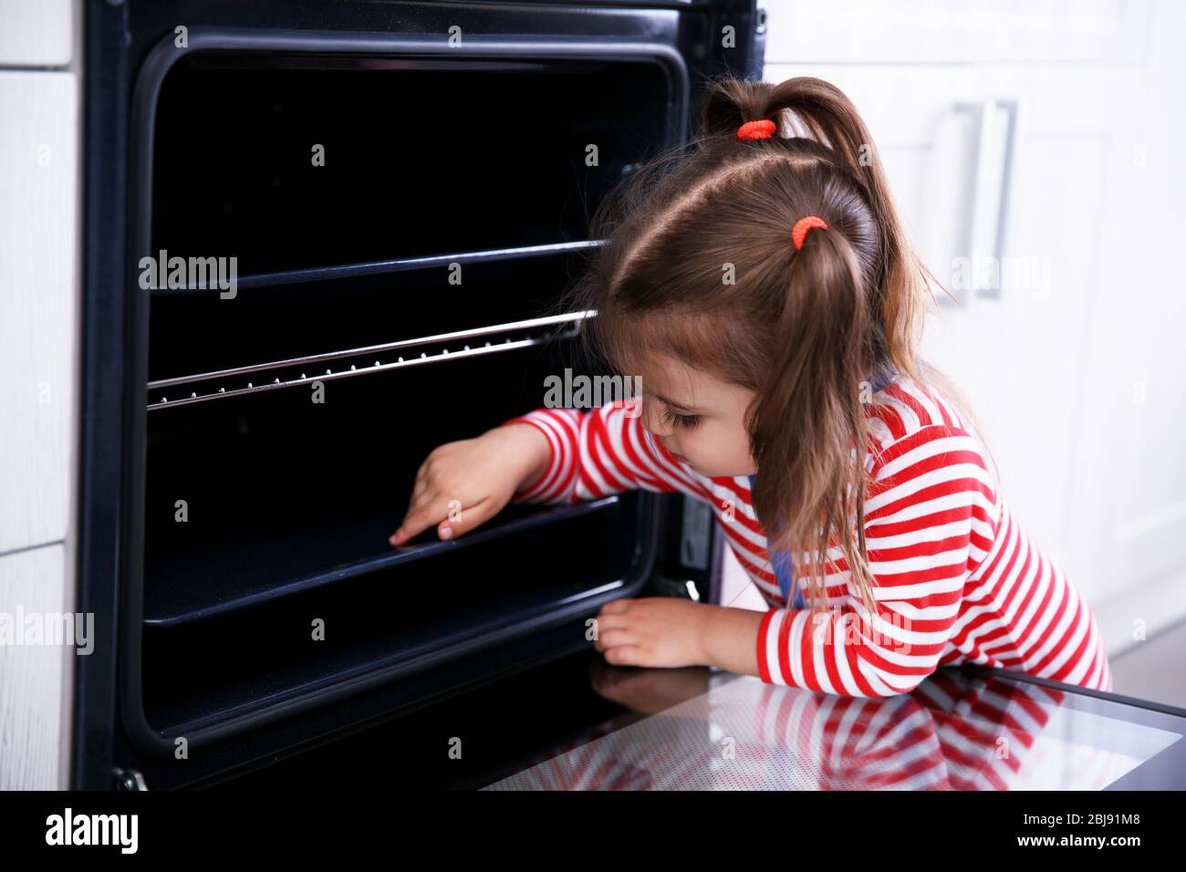 Little girl playing with oven in the kitchen Stock Photo - Alamy