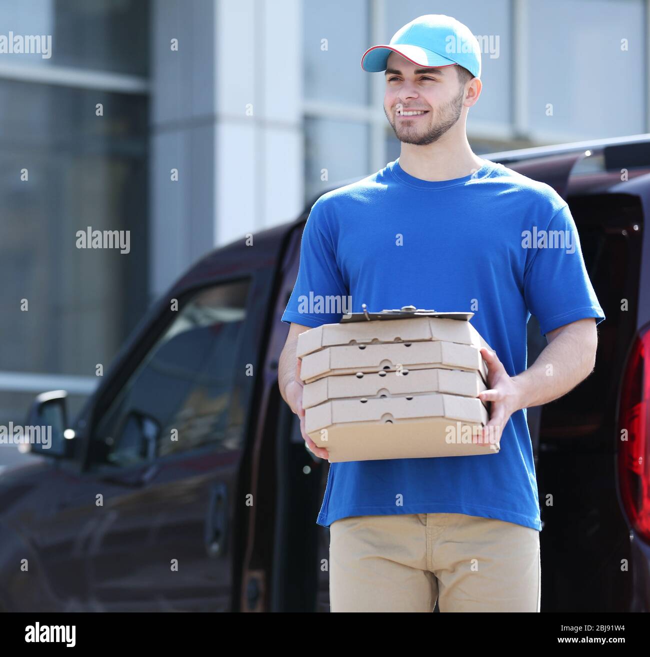 Young man holding pizza outside Stock Photo - Alamy