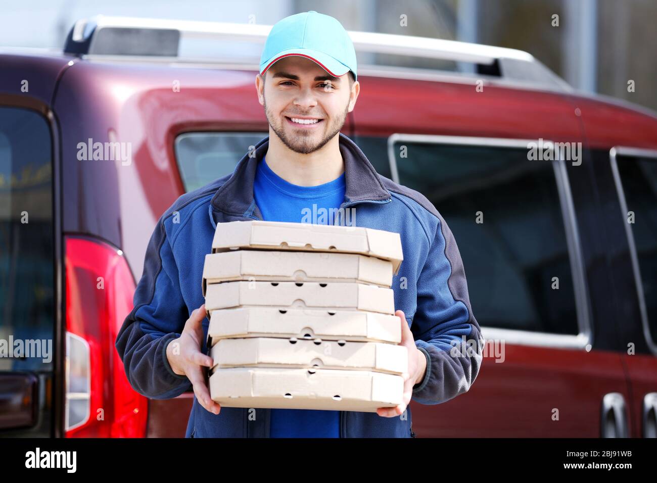 Young man holding pizza outside Stock Photo - Alamy
