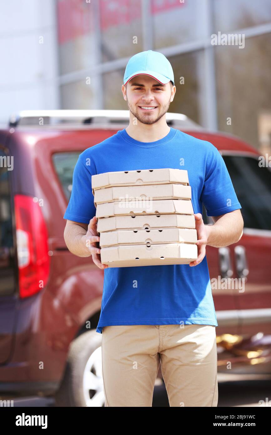 Young man holding pizza outside Stock Photo - Alamy