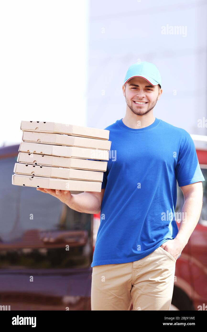 Young man holding pizza outside Stock Photo - Alamy