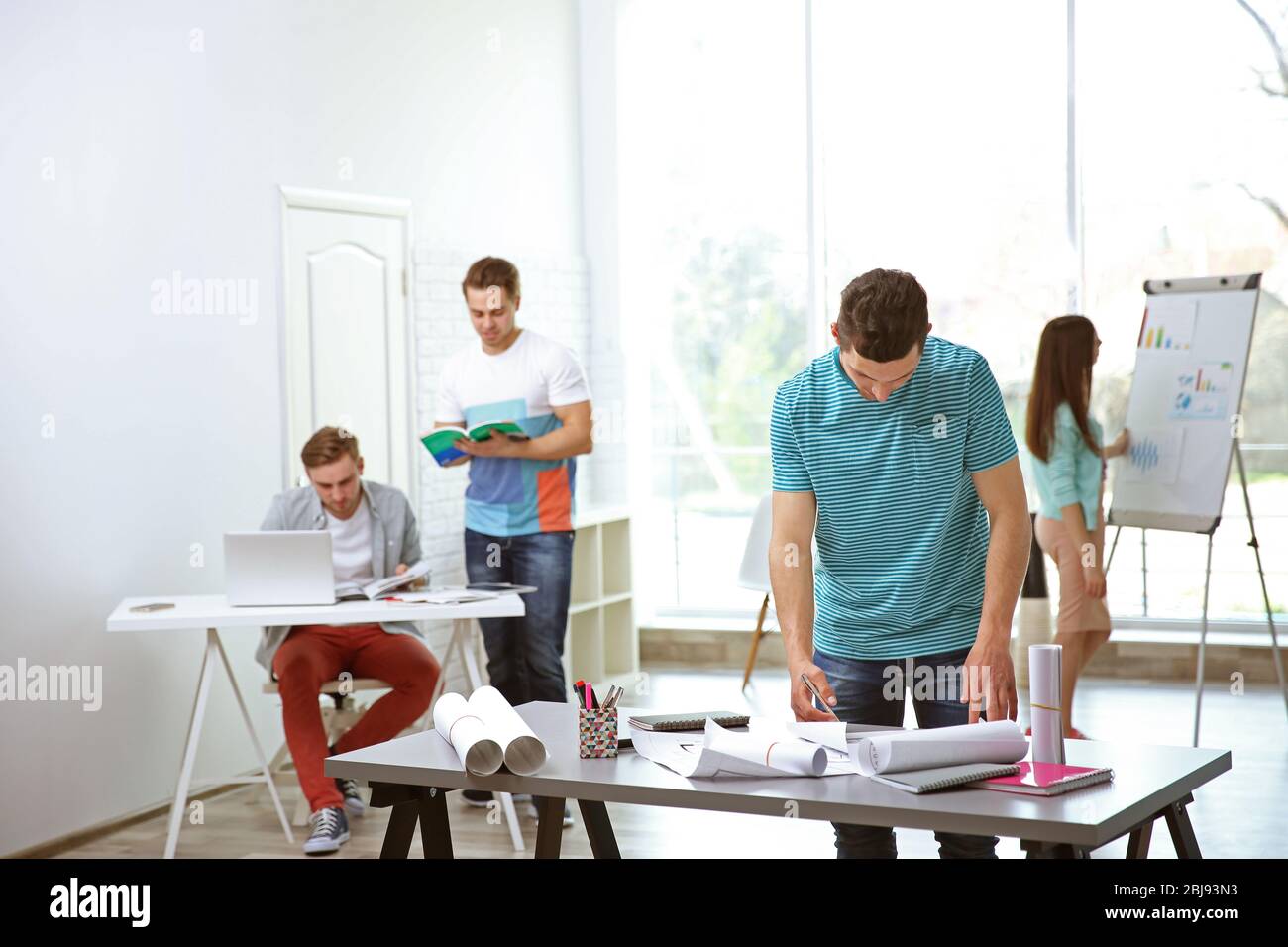 Young engineer working with blueprints at table indoors Stock Photo - Alamy