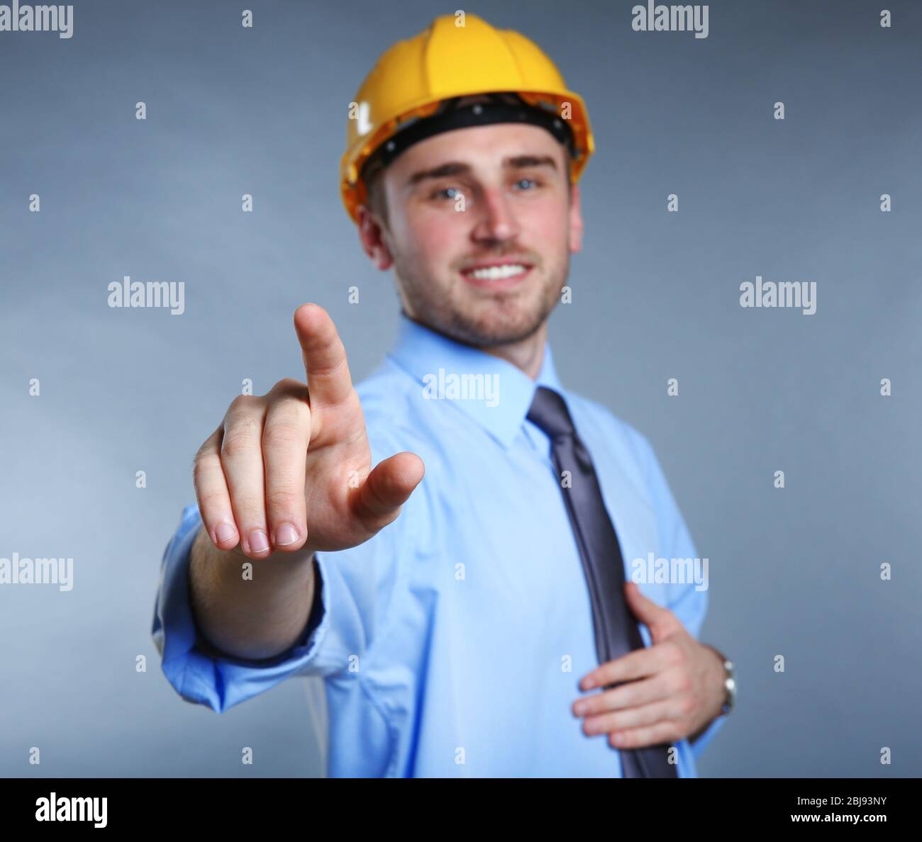 Man in helmet making sign with hand on grey background Stock Photo - Alamy