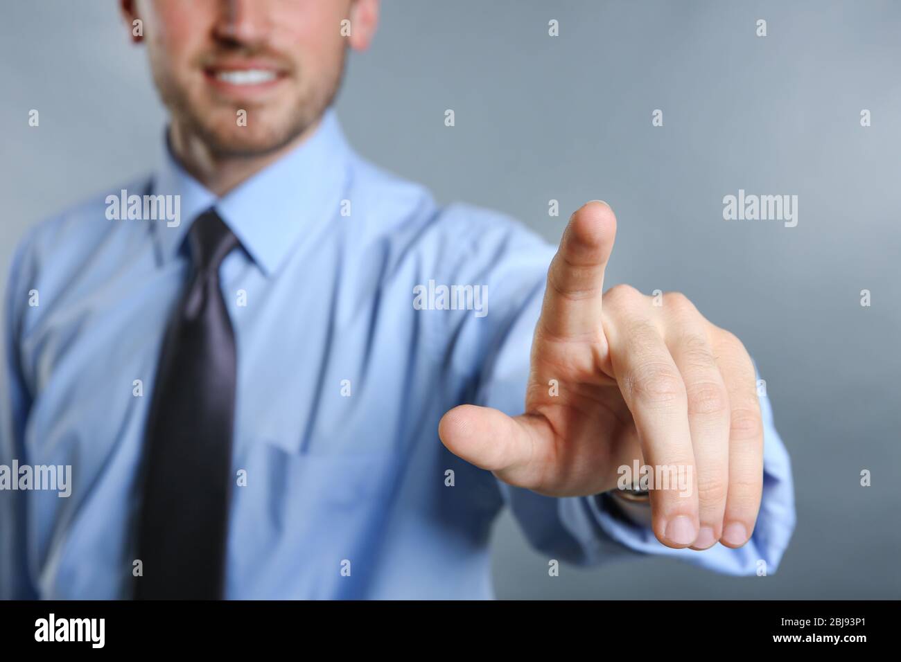 Male pointing finger on grey background Stock Photo - Alamy
