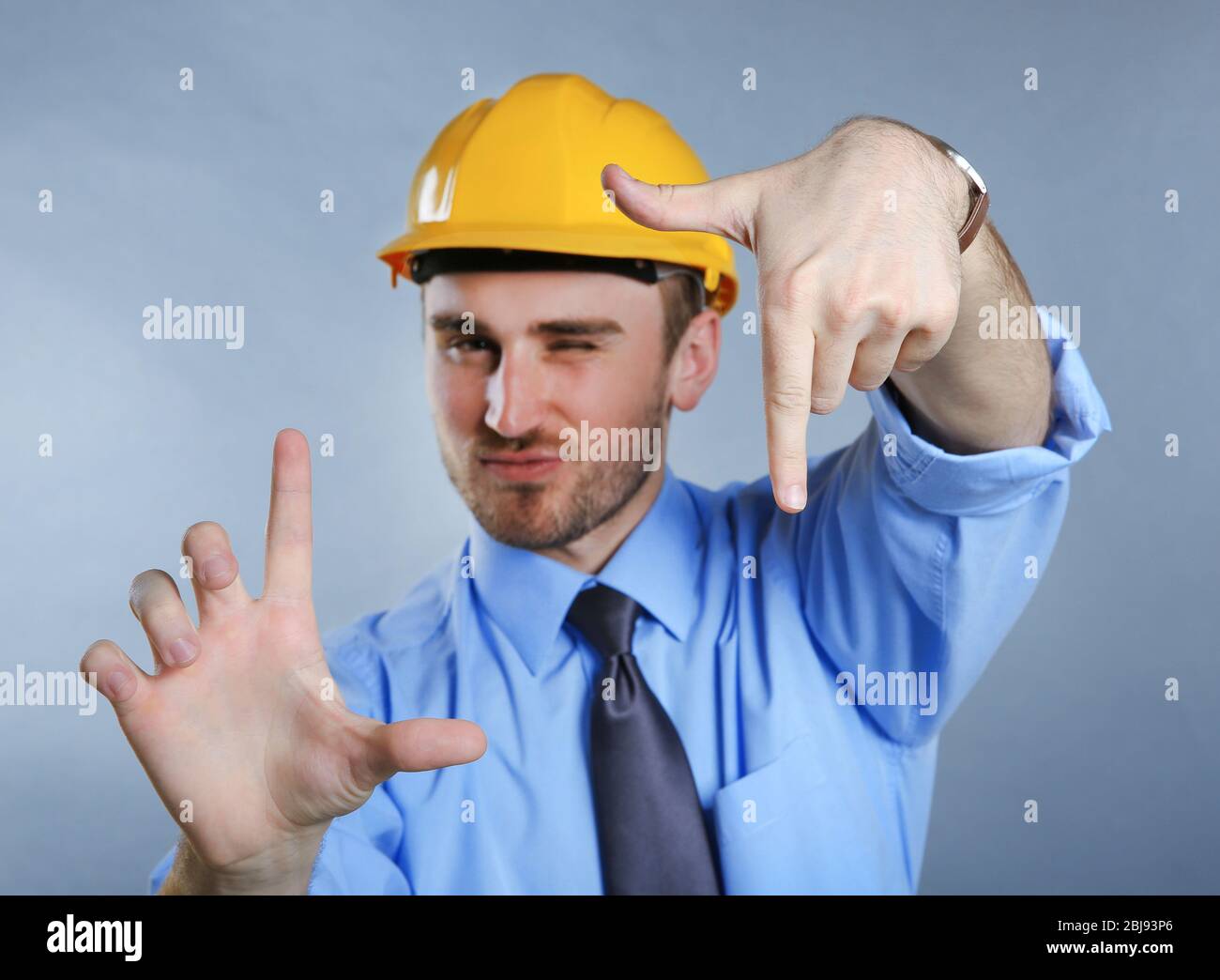 Man in helmet making sign with hands on grey background Stock Photo - Alamy