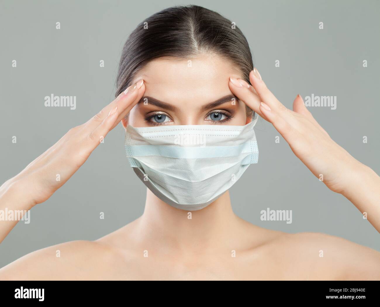 Woman in medical face mask with headache on white background Stock ...