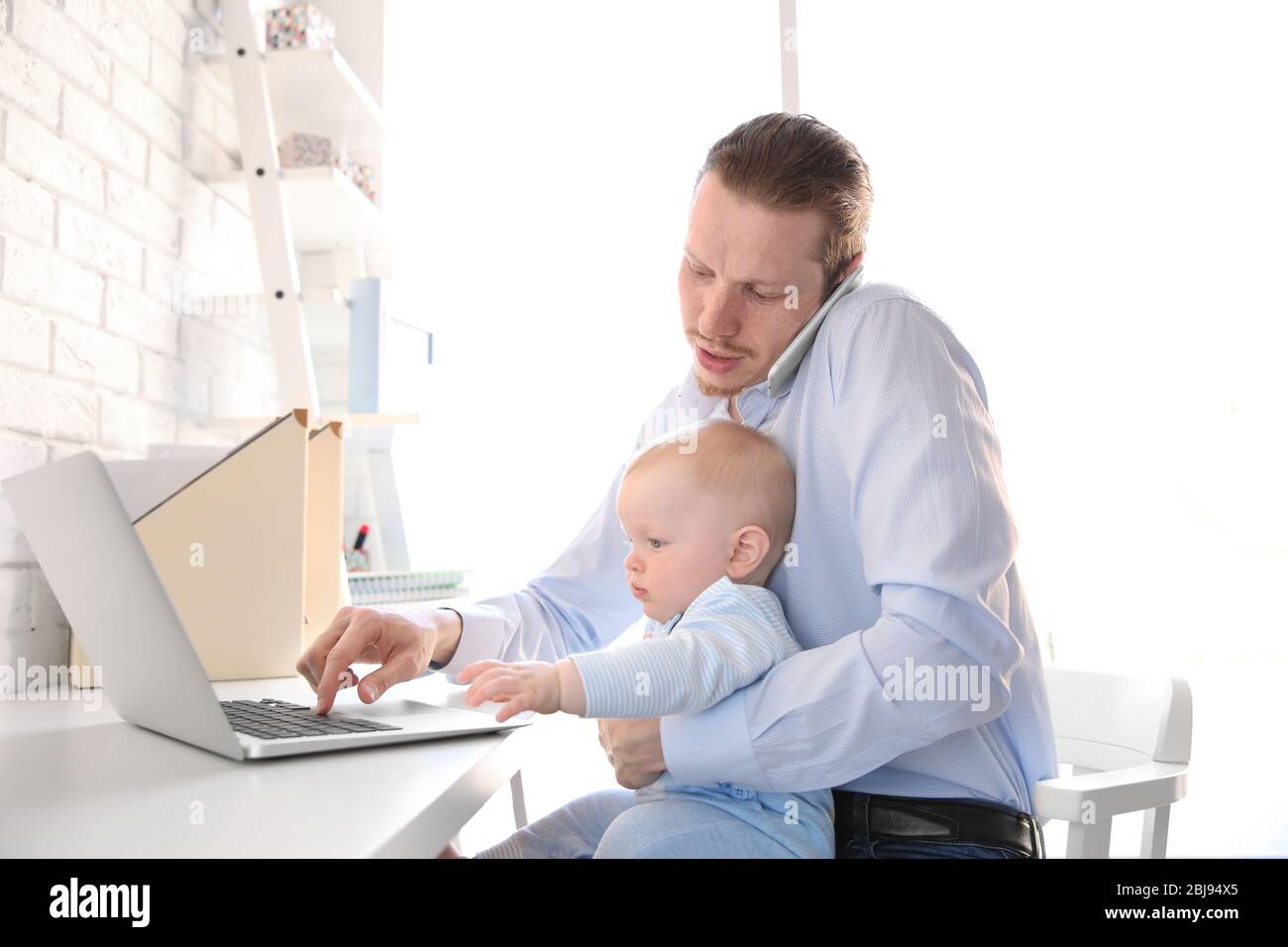 Young father with his little son working at home Stock Photo - Alamy