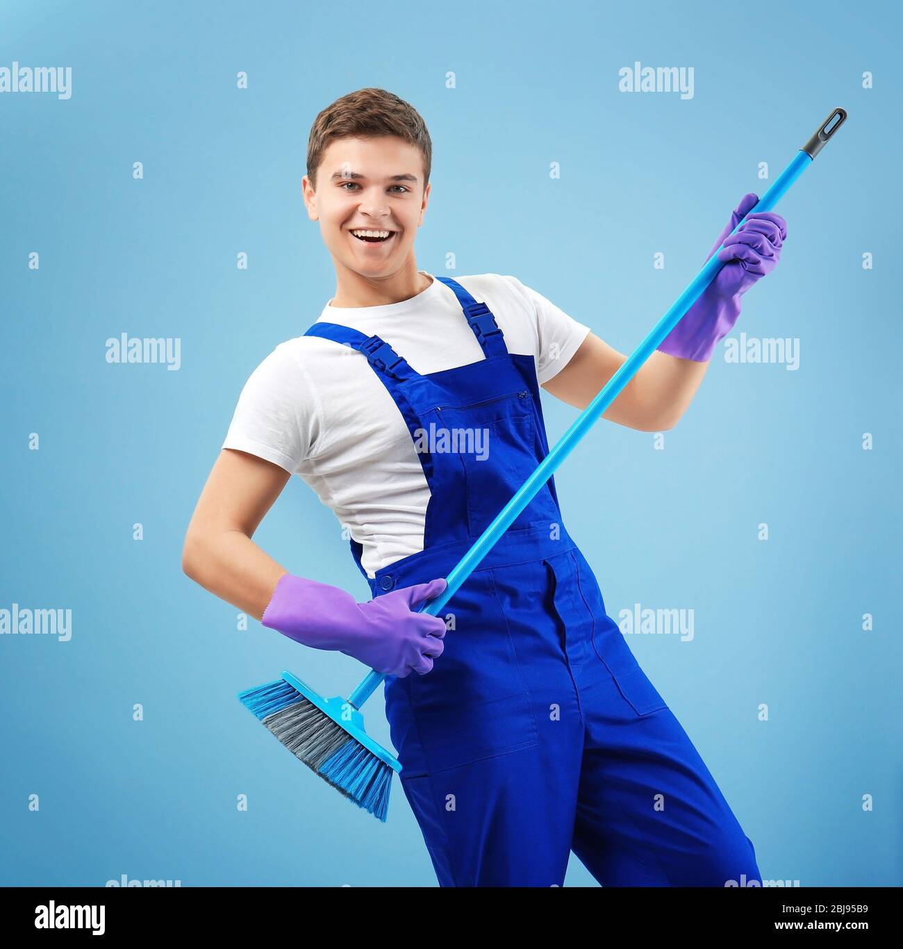 Man holding broom on grey background Stock Photo - Alamy