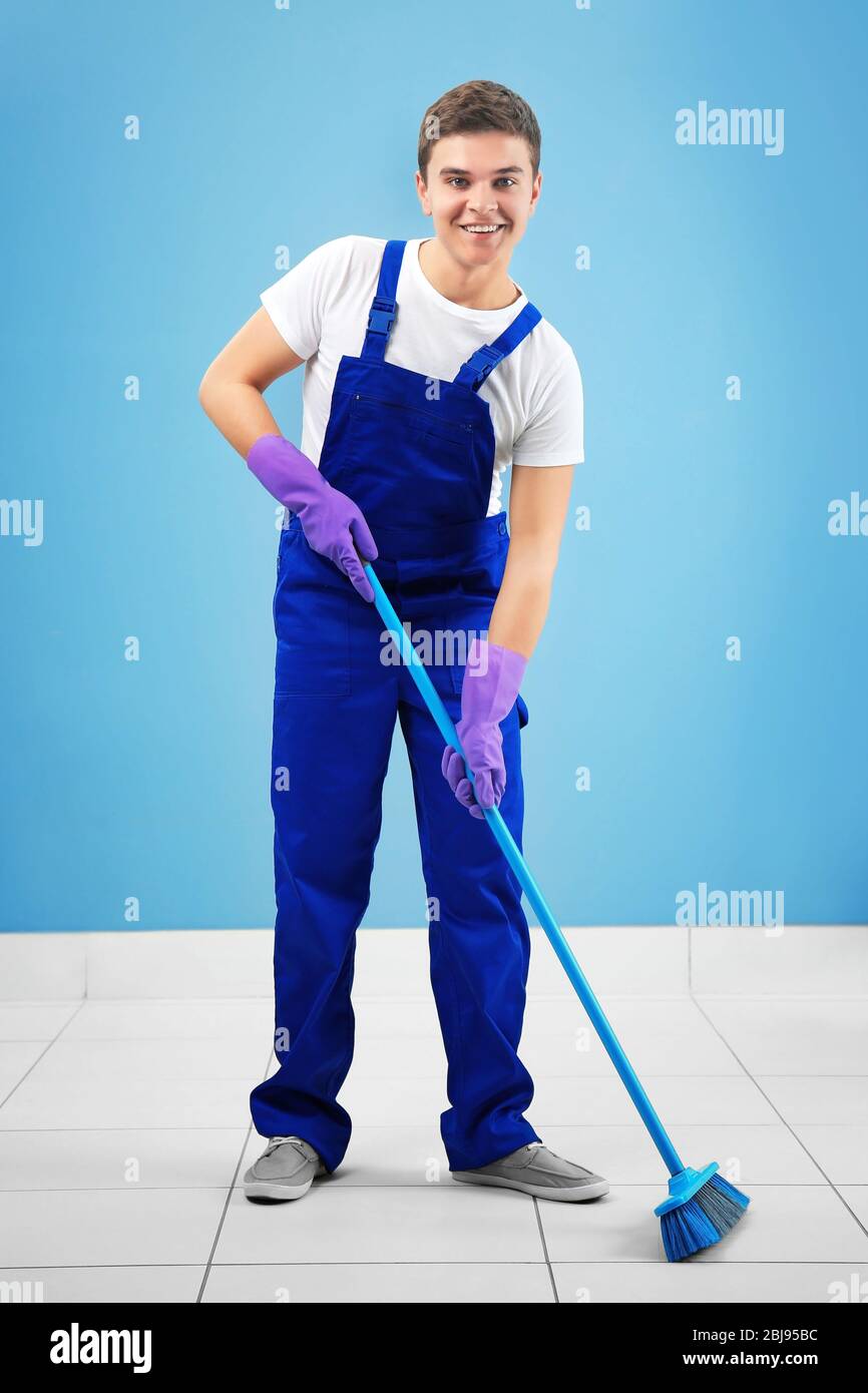 Man holding broom on grey background Stock Photo - Alamy