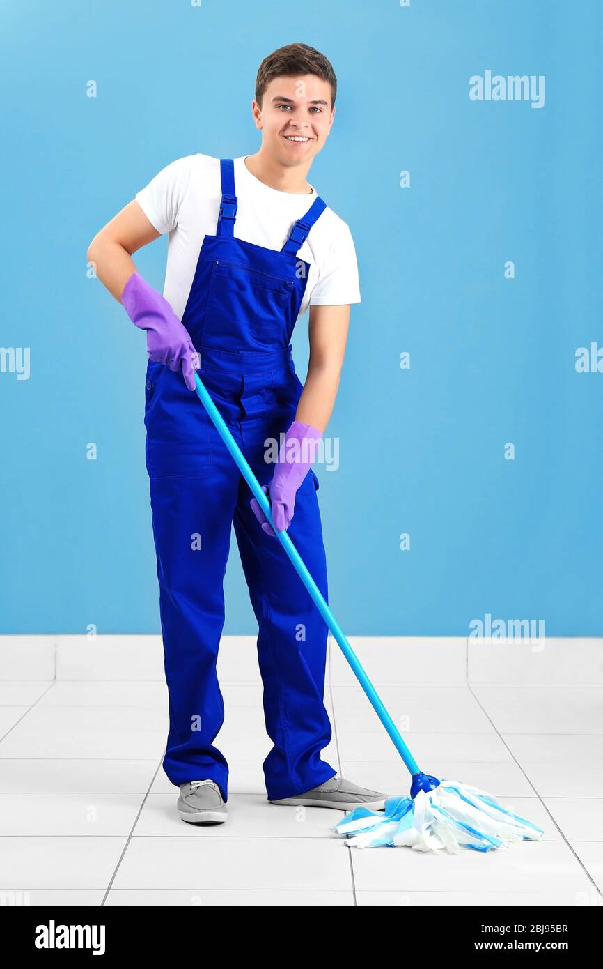 Man holding mop on grey background Stock Photo - Alamy