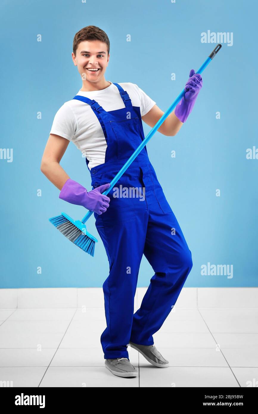 Man holding broom on grey background Stock Photo - Alamy