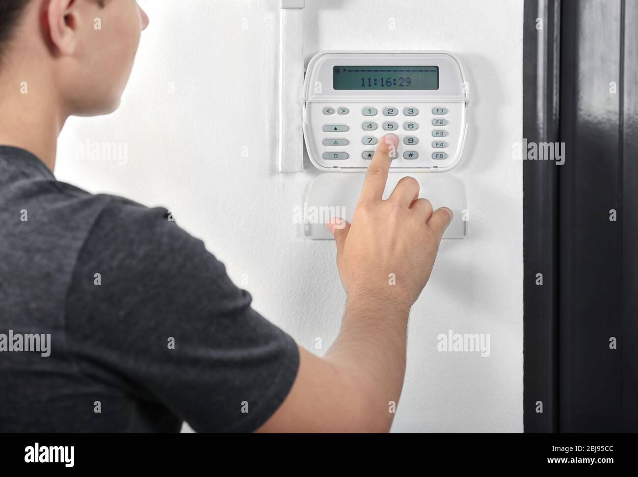Man pressing the code on a house alarm Stock Photo - Alamy