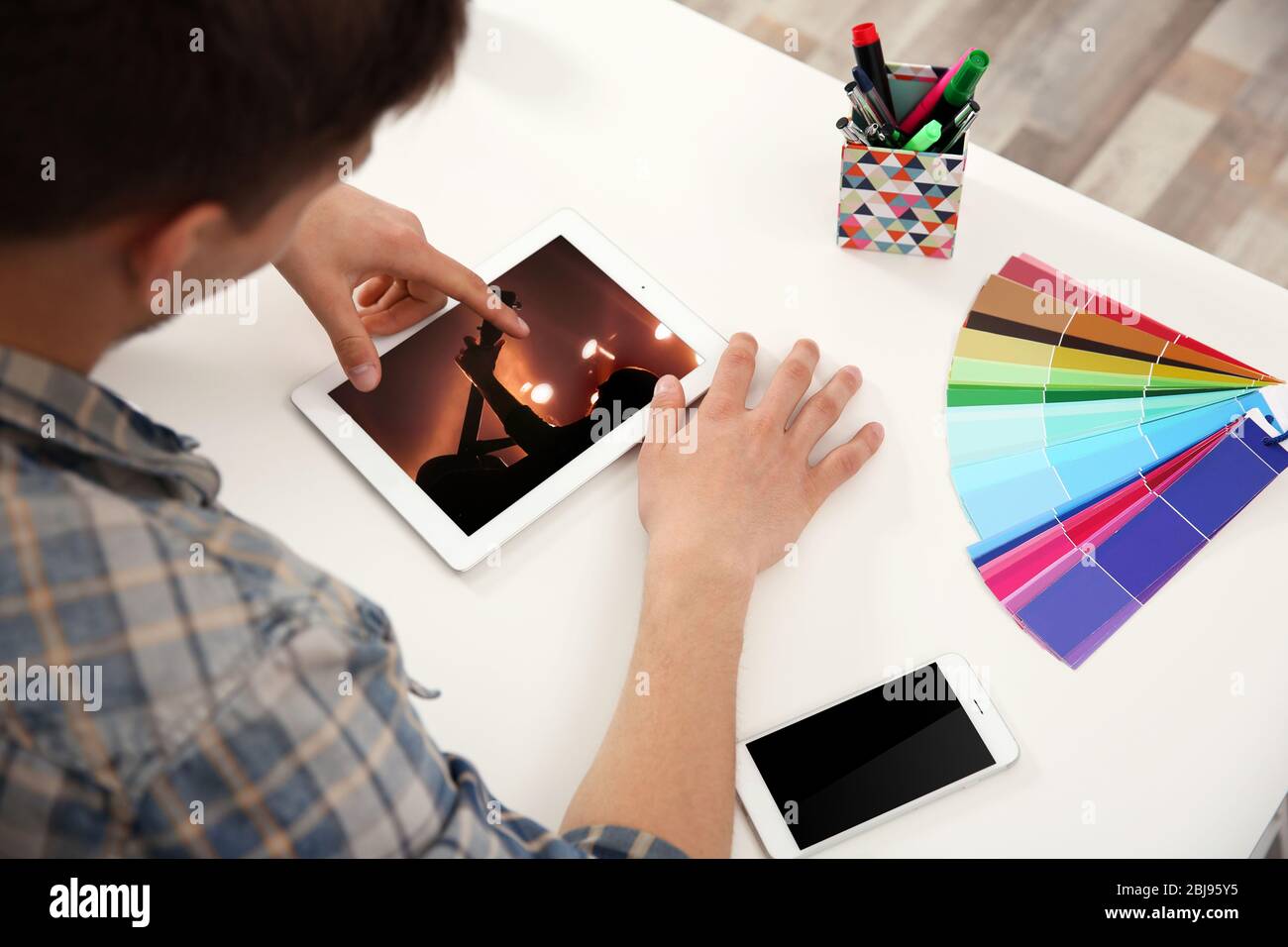 Man working with color palette and tablet at office Stock Photo - Alamy