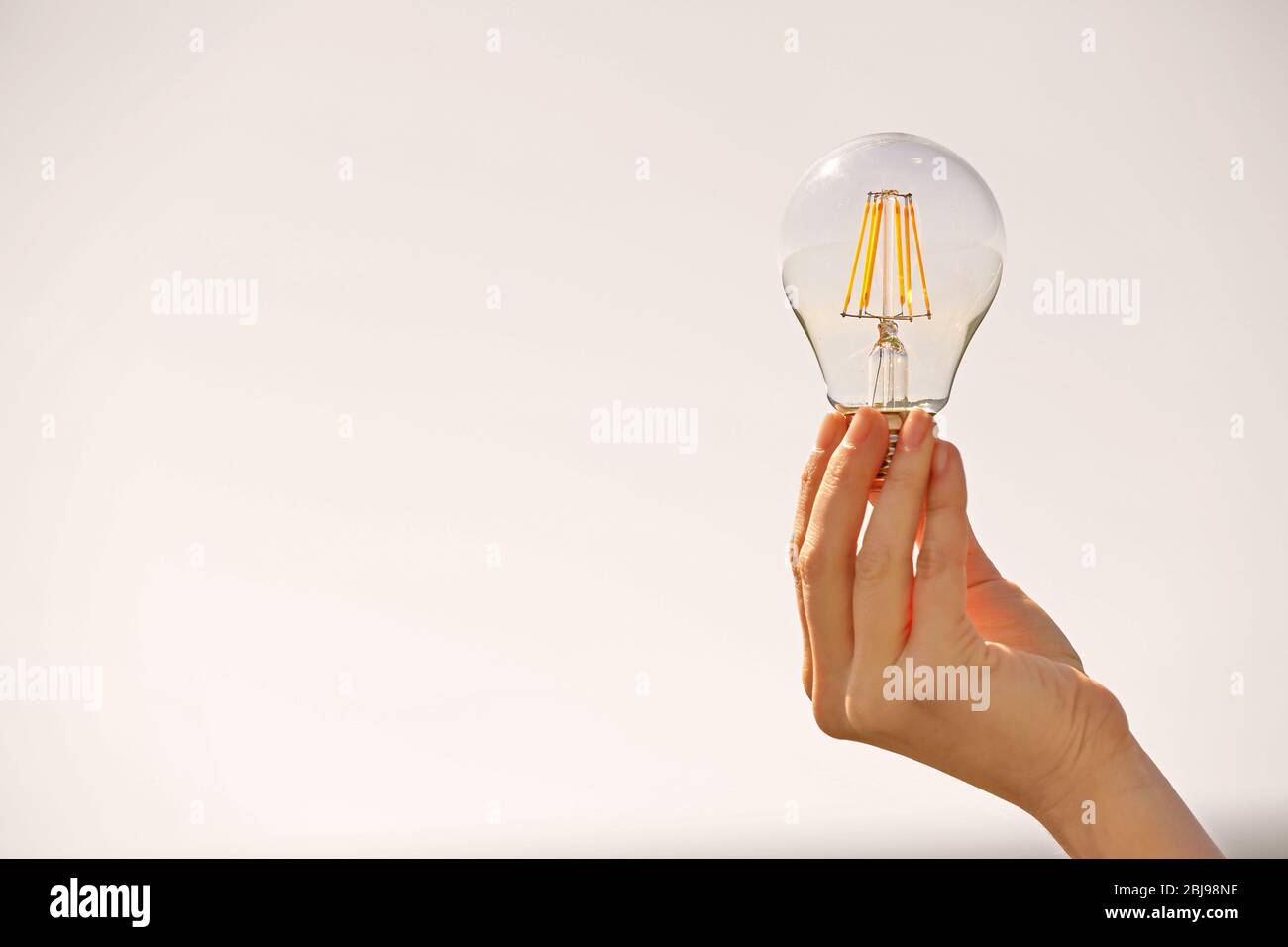 Hand holding lamp on sky background Stock Photo - Alamy