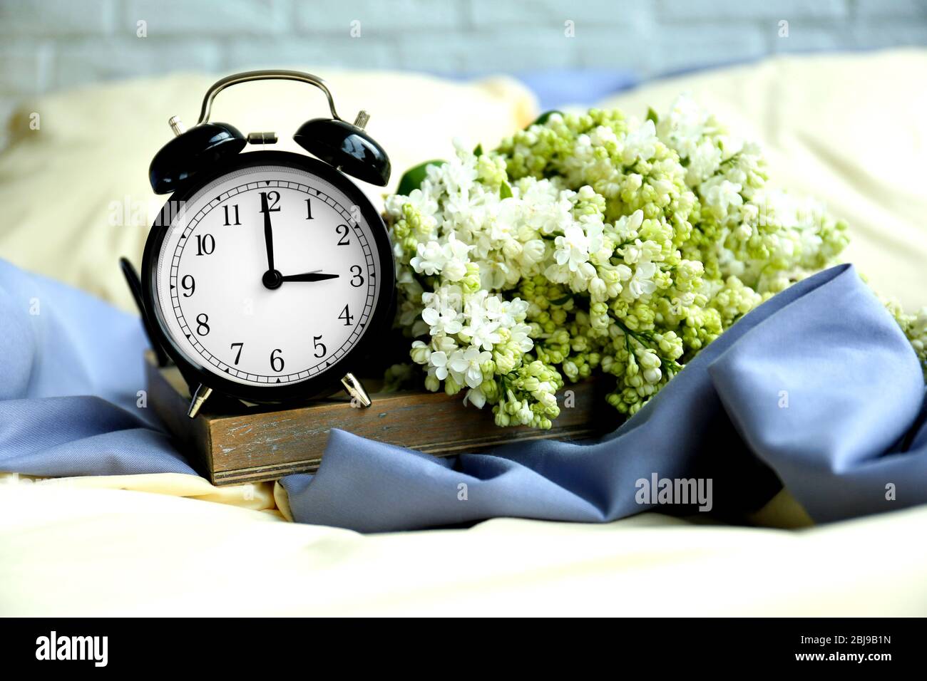 Alarm clock and flower bouquet on the bed Stock Photo - Alamy