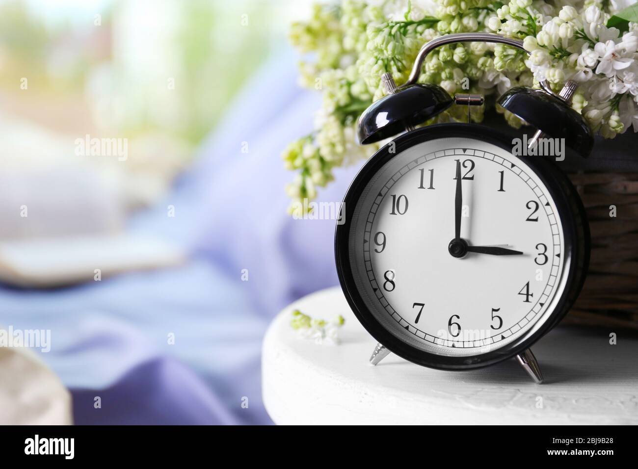 Alarm clock and flower bouquet on a side table by the bed Stock Photo ...
