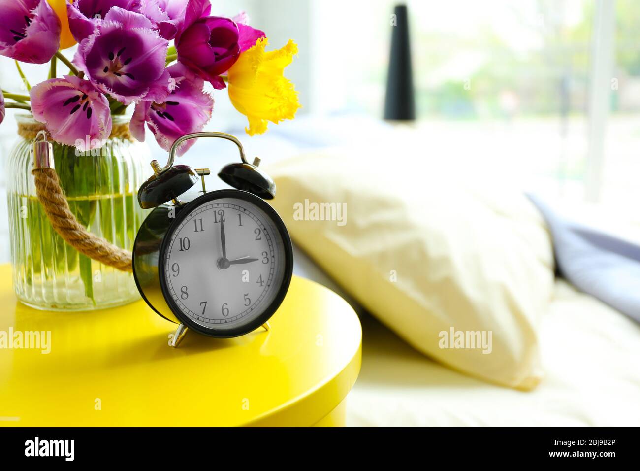Alarm clock and flower bouquet on a side table by the bed Stock Photo ...