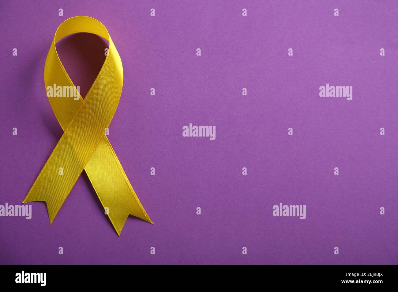 Yellow ribbon on purple background Stock Photo - Alamy