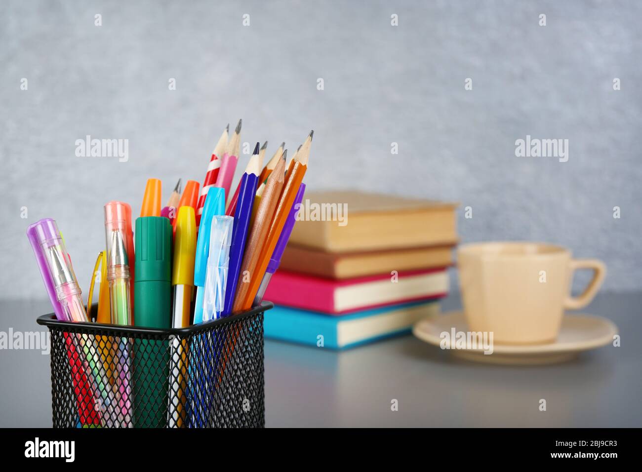 Colorful pencils and pens in metal holder on grey wall background Stock ...