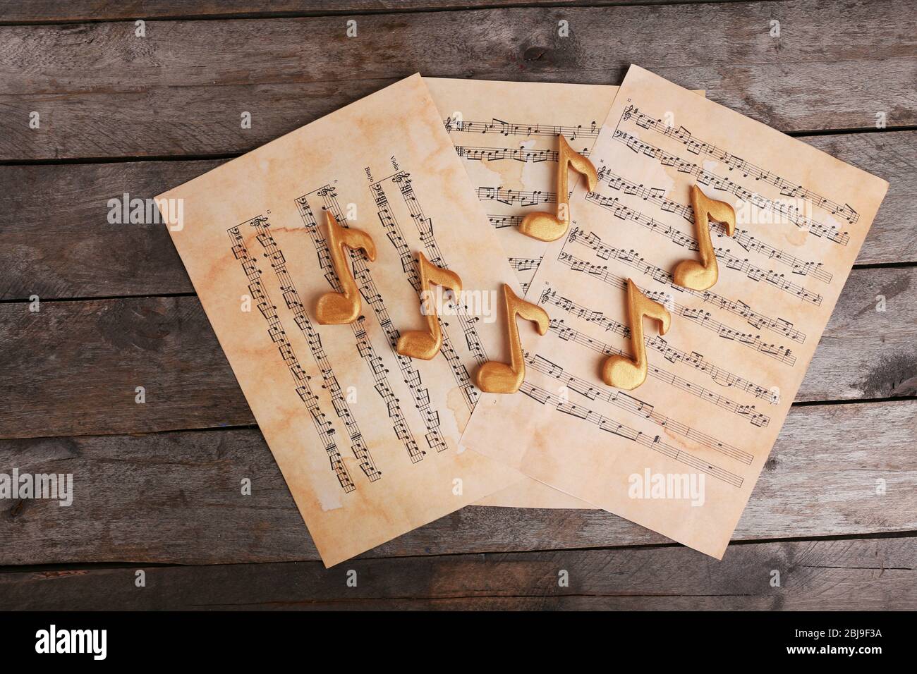 Golden music notes and sheets on wooden table, top view Stock Photo - Alamy
