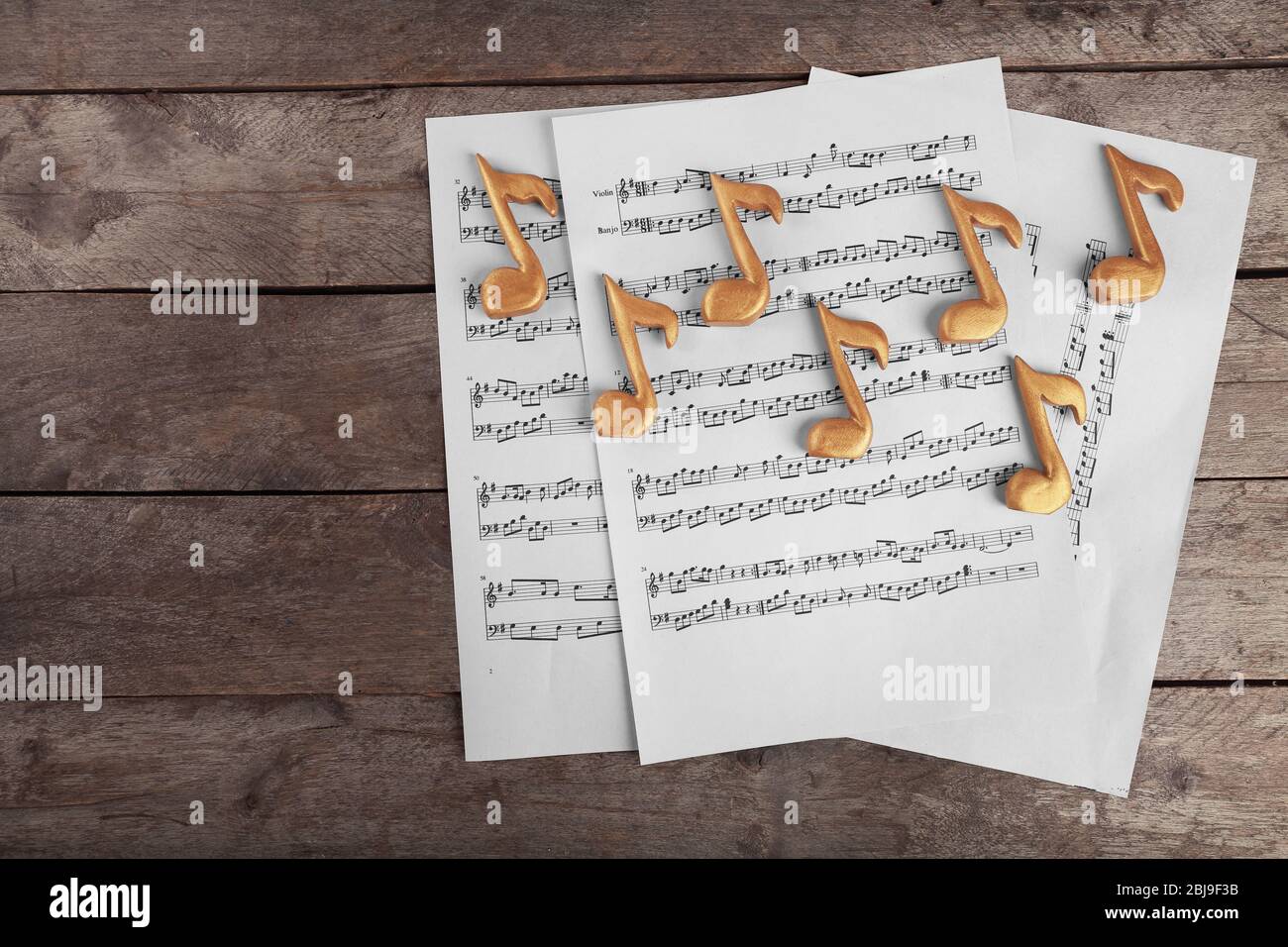 Golden music notes and sheets on wooden table, top view Stock Photo - Alamy