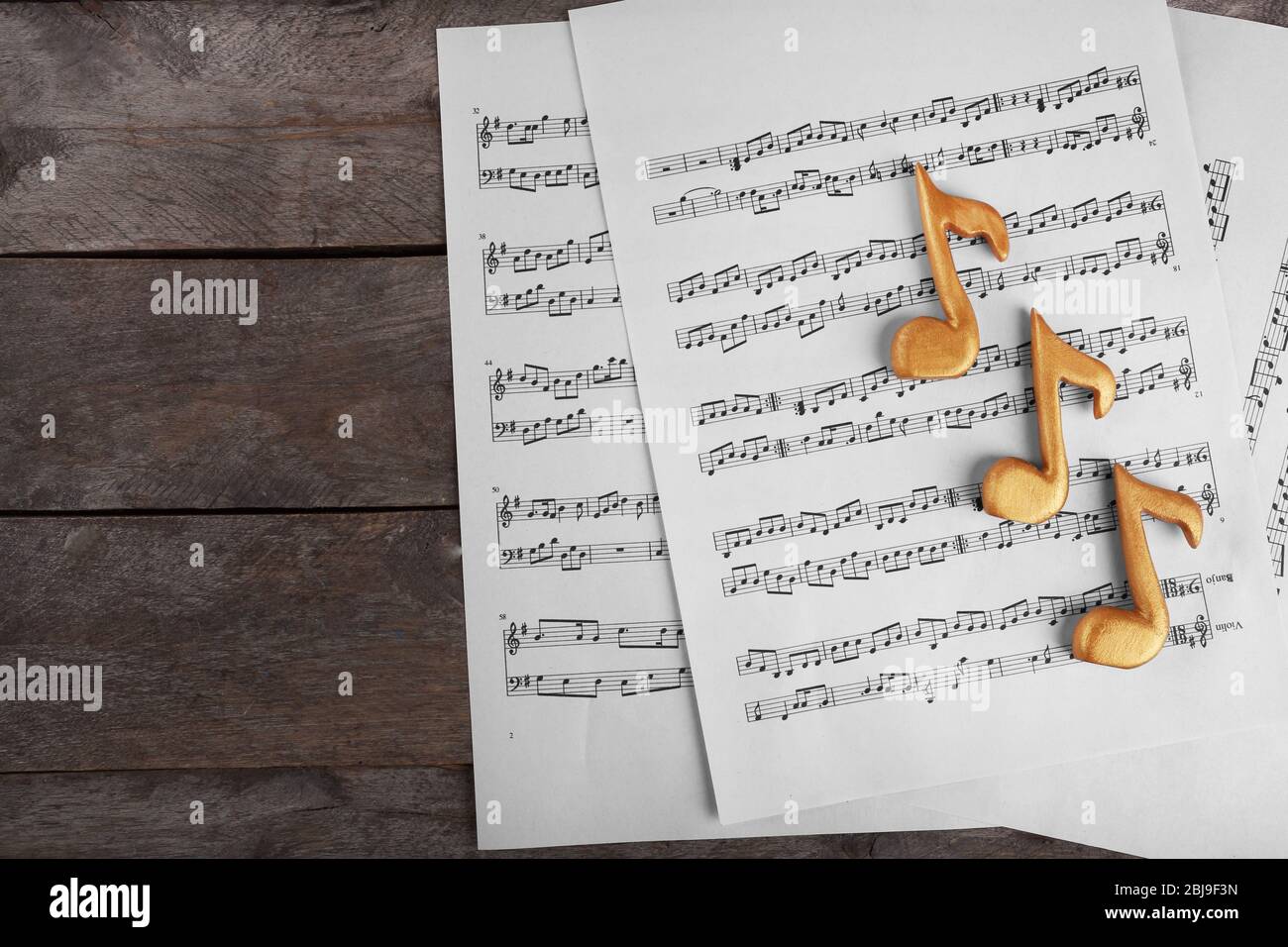 Golden music notes and sheets on wooden table, top view Stock Photo - Alamy