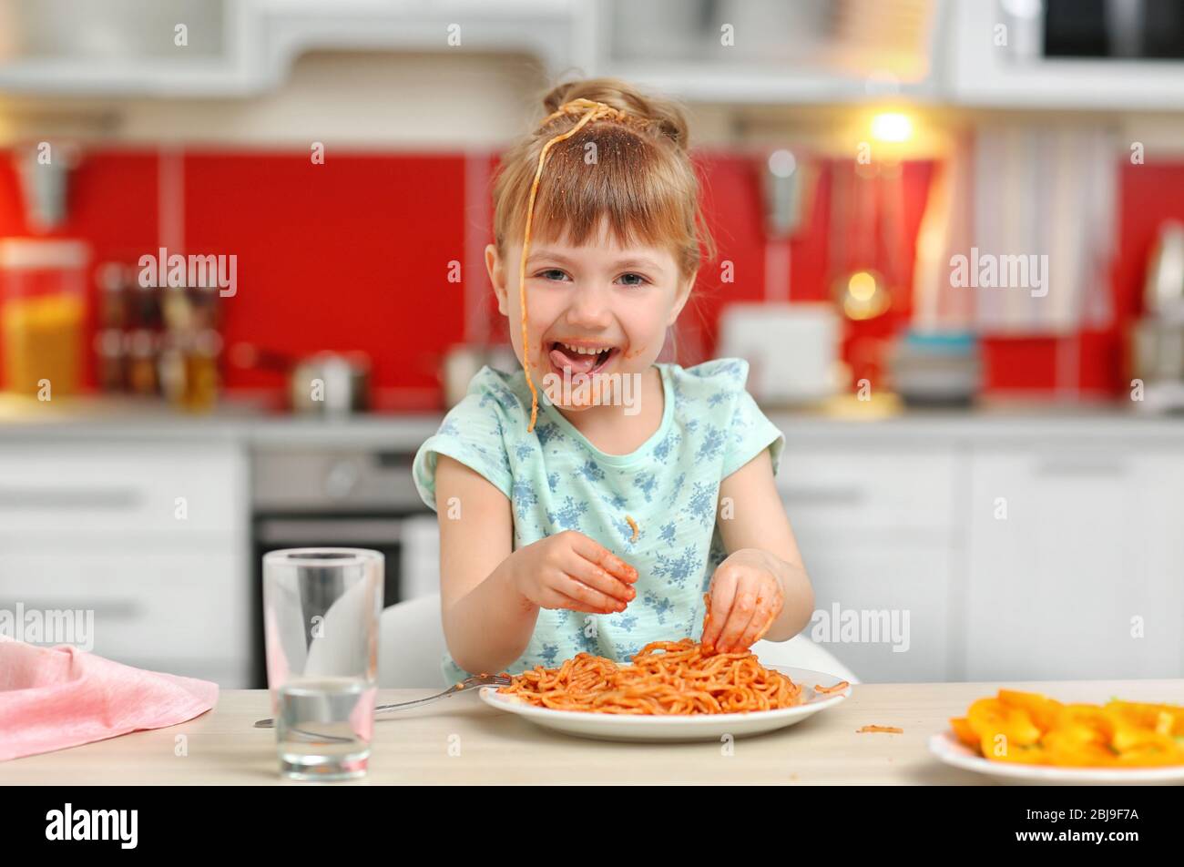 Adorable little girl eating spaghetti at table Stock Photo - Alamy