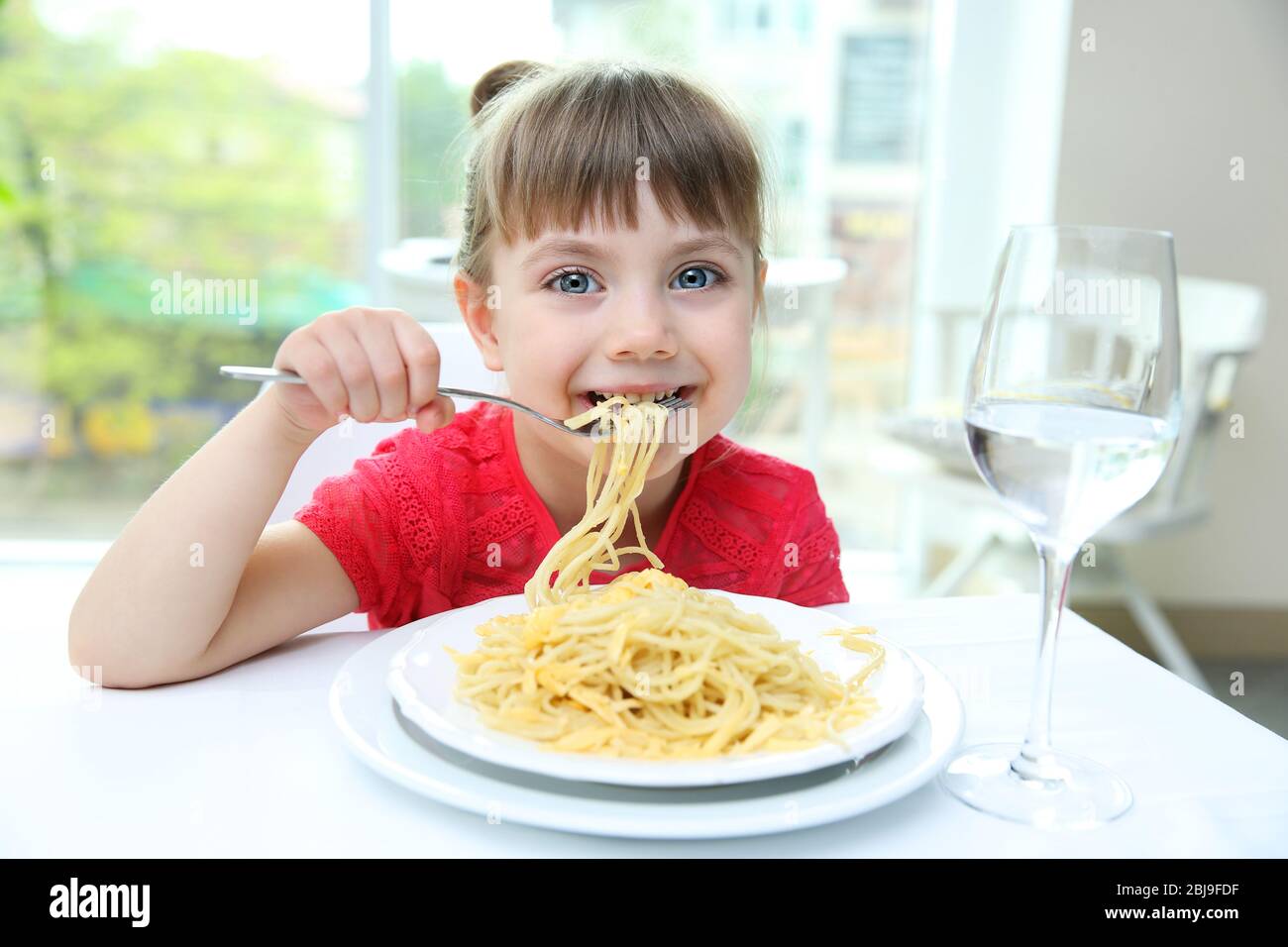 Beautiful small girl eating pasta Stock Photo - Alamy