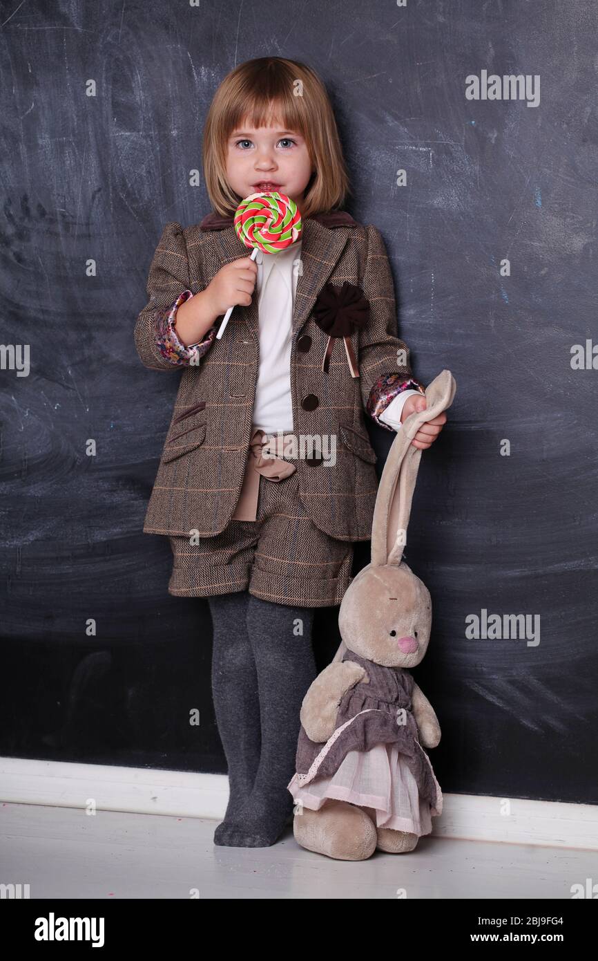 Beautiful cute little girl with toy eating lollipop Stock Photo - Alamy