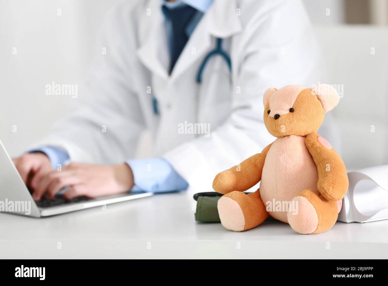 Pediatrician doctor with teddy bear and laptop in office Stock Photo ...